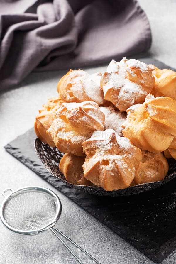 Profiteroles with Custard and Powdered Sugar on a Plate. Concrete Grey ...