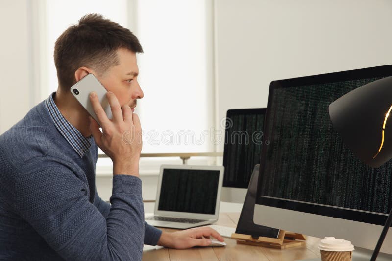 Programmer Talking on Phone while Working at Desk in Office Stock Photo ...