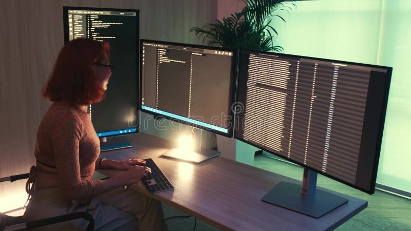 Programmer Woman Works at Multi-monitor Desktop Setup in Dim Office ...