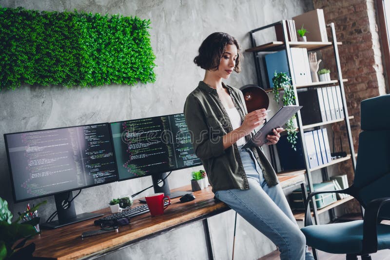 Young Female Programmer Working Remotely in a Stylish Office Environment Analyzing Data on a ...