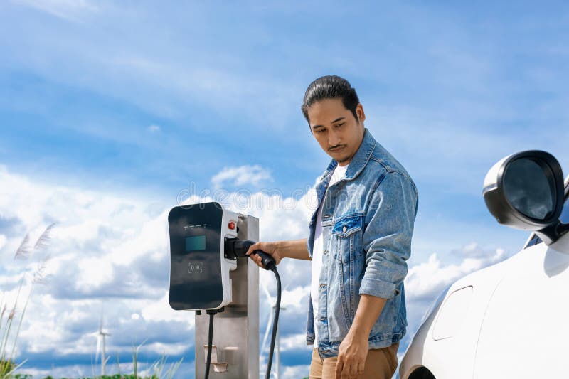 Progressive Man with Plugged-in EV Car with Charging Point, Cloudscape ...