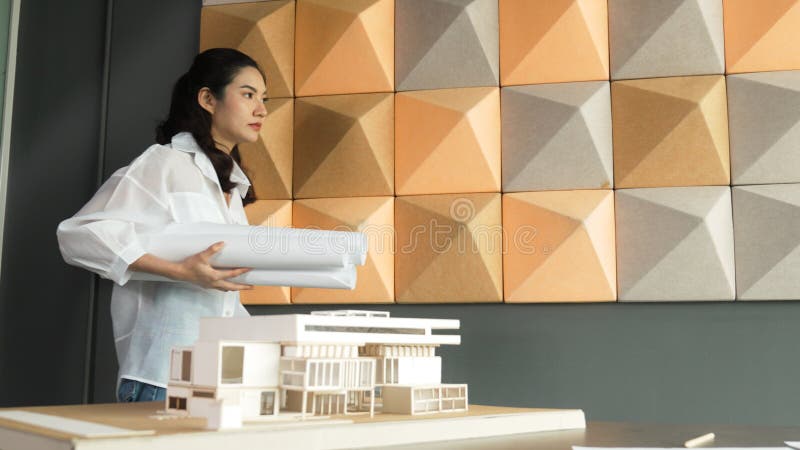 Project Manager Holds Project Plan while Standing Near House Model ... Project Manager Holds Project Plan while Standing Near House Model ...