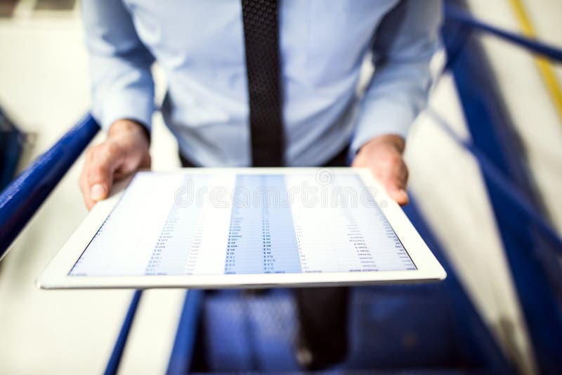 Project Manager Standing in Modern Industrial Factory, Holding Tablet ...