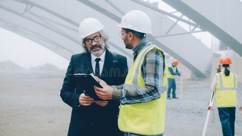 Engineers Talking To Project Manager Standing at Construction Site ...