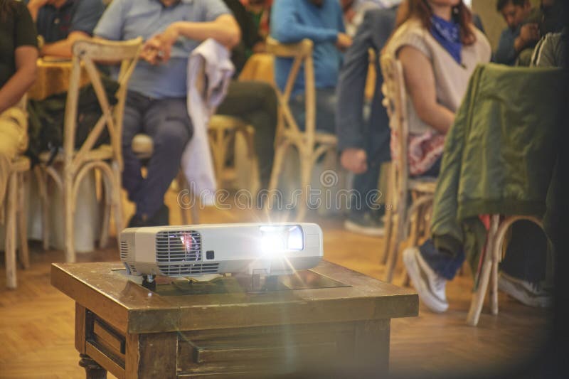 A Projector is on a Table in Front of a Group of People Stock Photo ...