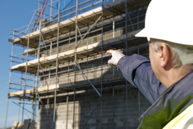 Property Developer / Builder Pointing at Building with Scaffolding ...