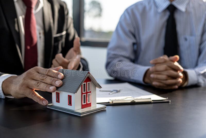 The Property Salesman on the Project is Pointing To a Model of a Small ...