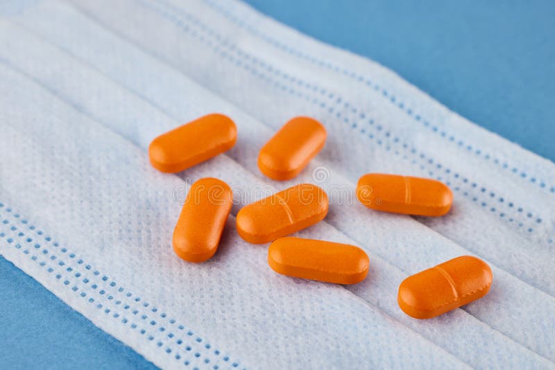 Protective Face Mask, Orange Pills on a Blue Background. the Concept of ...