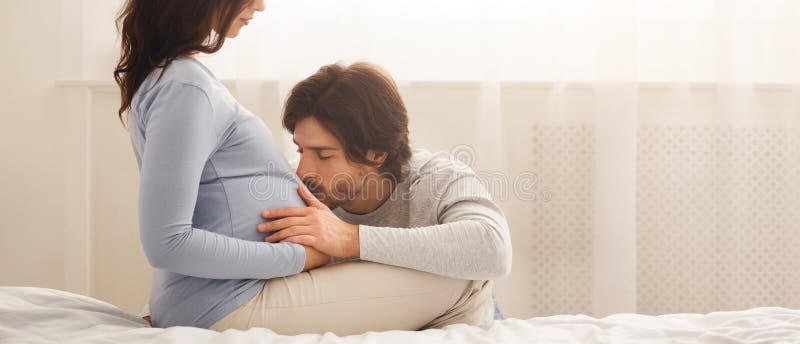 Proud Husband Kissing His Pregnant Wifeand X27 S Belly On Bed At Home
