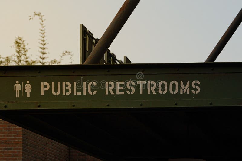 Public Restrooms Sign on a Green Metal Structure in a Clear Sunset ...