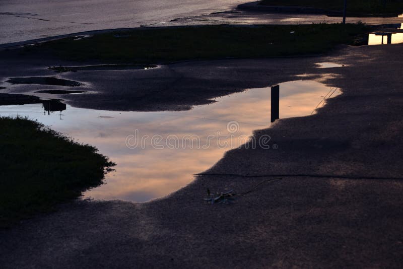 A Puddle on the Asphalt with a Reflection of the Evening Sky Stock ...