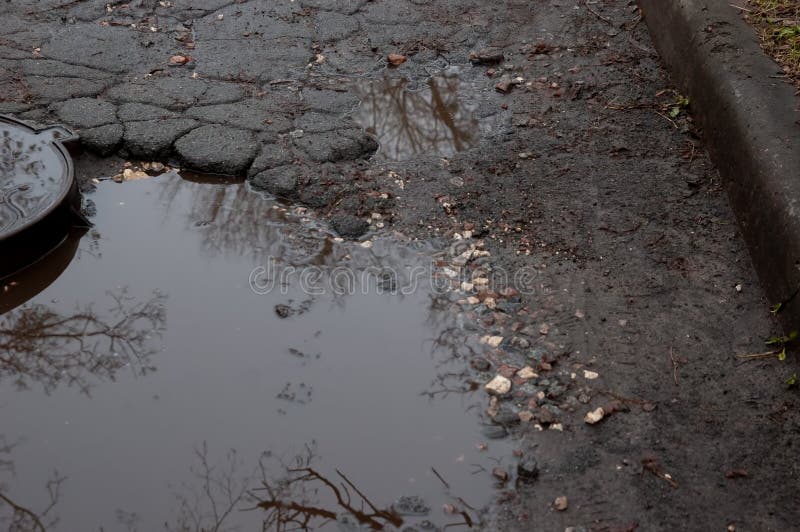 Puddle in a Deep Hole in an Asphalt Road Near a Sewer Manhole Stock ...