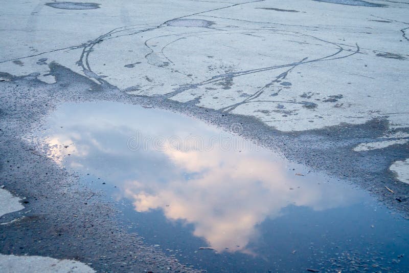 A Puddle on the Paved Road. Reflection of the Blue Sky and White Clouds ...