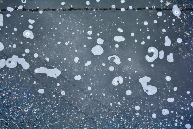 Puddle on the Pavement of a City Road with Spots of White Foam and ...