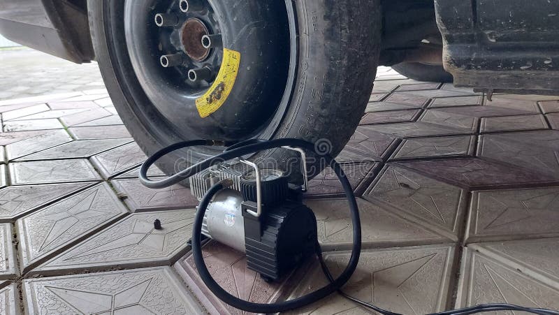 Pumping a Spare Wheel on the Car Using an Air Compressor. Wheel Hub and ...
