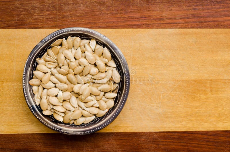 Pumpkin Seeds Inside a Small Bowl on a Two-colored Wooden Surface. Top ...