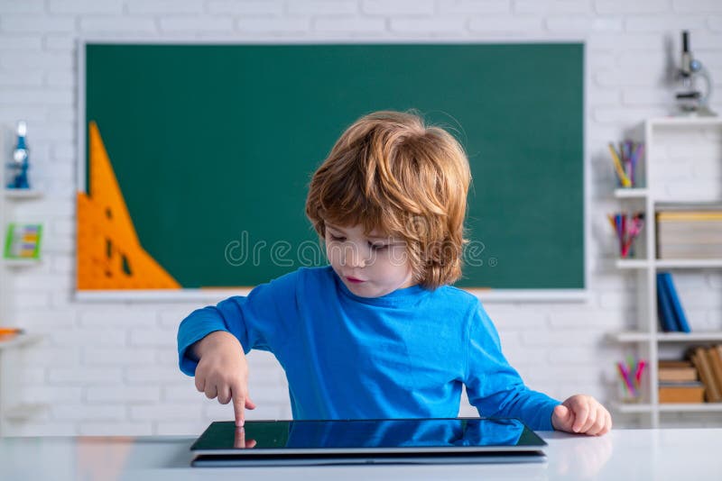 Pupil with Digital Tablet in School Classroom. Little Boy Playing with ...