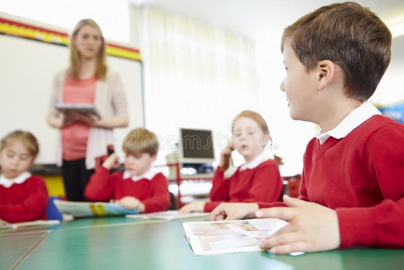 Pupils Sitting at Table As Teacher Stands by Whiteboard Stock Image ...