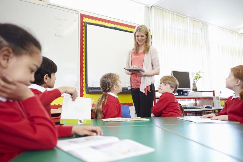 Pupils Sitting at Table As Teacher Stands by Whiteboard Stock Image ...