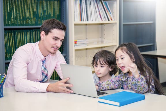Pupils Studying with Teacher Using Computer Device in Classroom Stock ...