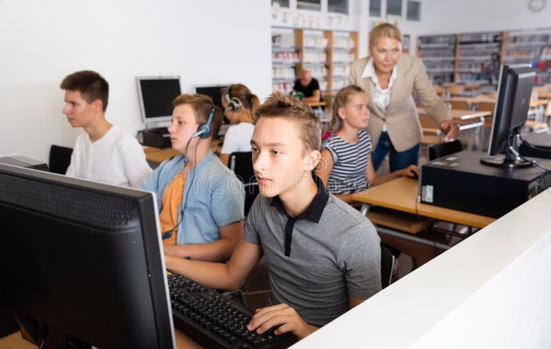 Pupils Using Computers at Lesson, Teacher Teaching Them in Class Room ... Pupils Using Computers at Lesson, Teacher Teaching Them in Class Room ...