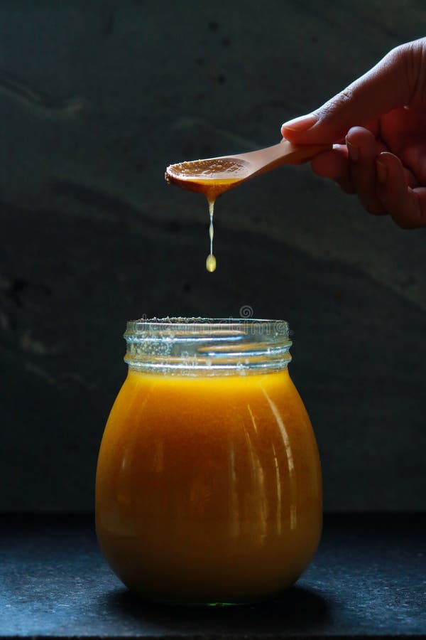 Pure Ghee Dripping from a Wooden Spoon into a Jar Stock Image - Image ...