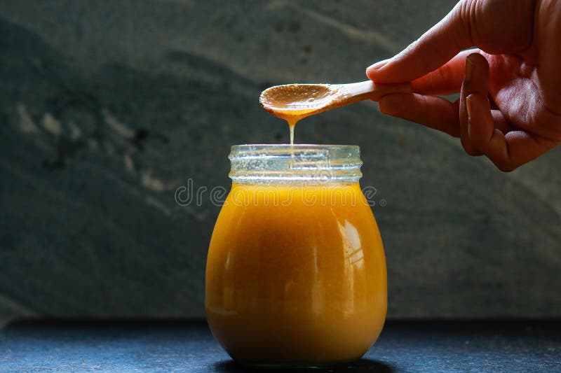 Pure Ghee Dripping from a Wooden Spoon into a Jar Stock Image - Image ...