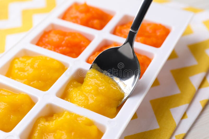 Putting Puree with Spoon into Ice Cube Tray on Table, Closeup. Ready ...