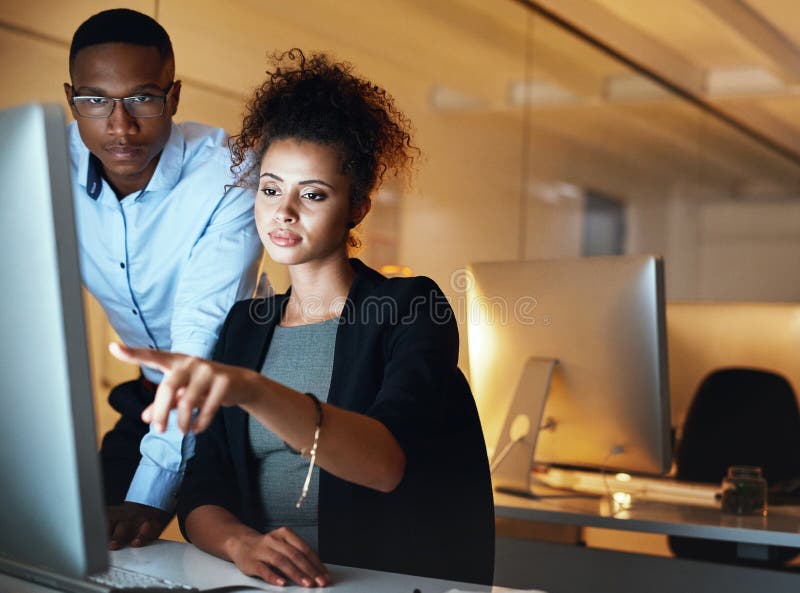 Putting in Some Overtime. Two Businesspeople Working Together on a ...
