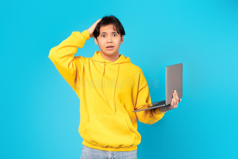 Puzzled Japanese Teen Guy Holding Laptop Touching Head, Blue Background ...