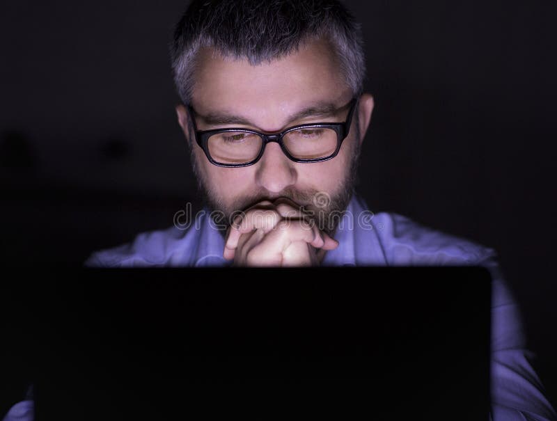 Puzzled Man Looking at Laptop Screen in Dark Room Stock Image - Image ...