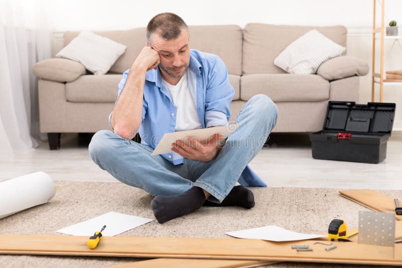 Man Assembling Furniture Pointing Finger Up Sitting On Floor Indoor