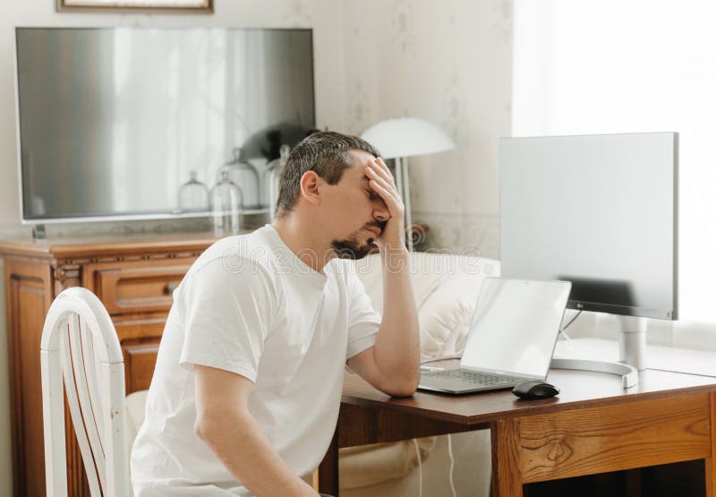 Puzzled Man at a Table with a Computer with a Hand Near His Face Stock ...