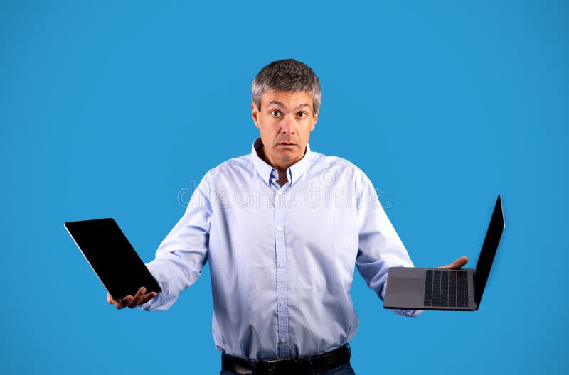 Puzzled Mature Man Holding Tablet and Laptop Choosing, Studio Shot ...