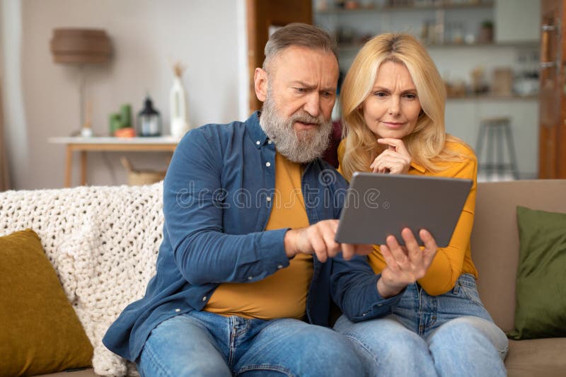 Puzzled Senior Couple Using Digital Tablet Browsing Internet at Home ...