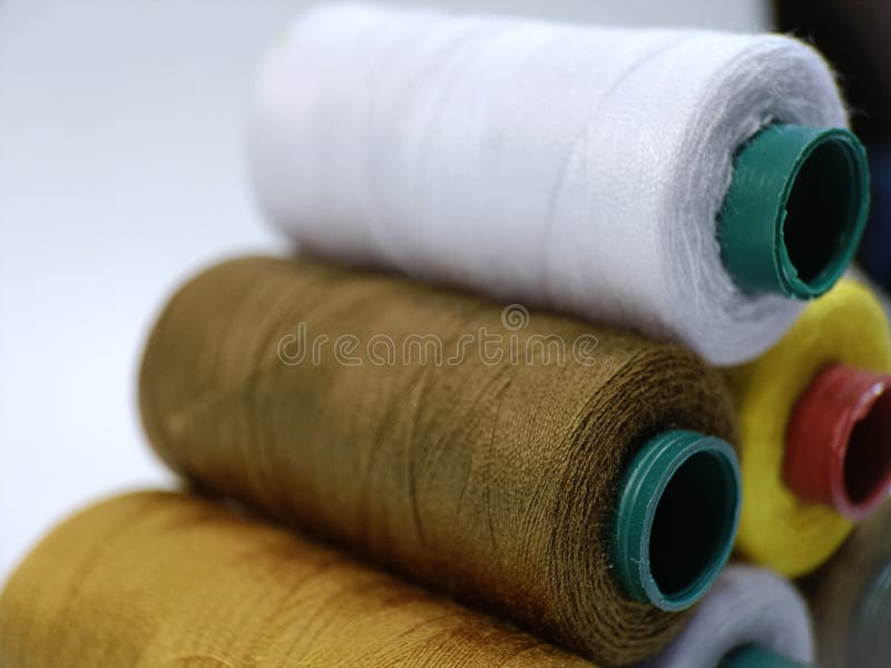 Pyramid Stack of Yellow, White, and Brown Sewing Thread Spools on White ...