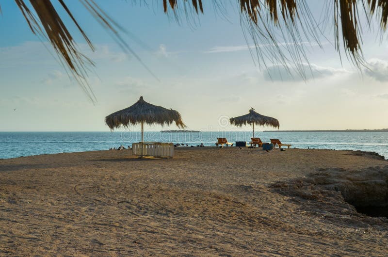 An Isolated Beach with Rustic Umbrellas and Deck Chairs Stock Image ...