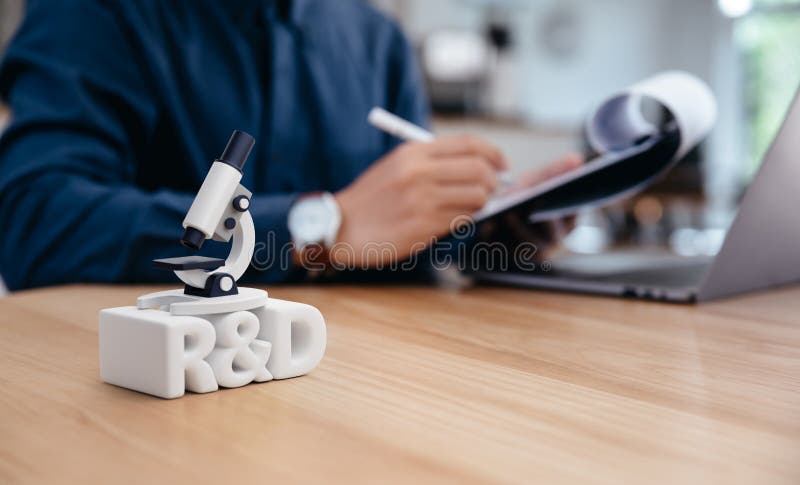 R D and Microscope on Table in Front of Working Business Man. Stock ...