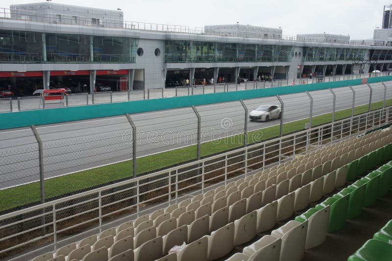 Racing Car Passes in Front of the Grandstand with the Paddock Building ...