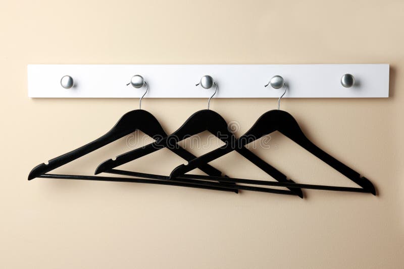 Rack with Empty Black Clothes Hangers on Beige Wall Stock Image - Image ...