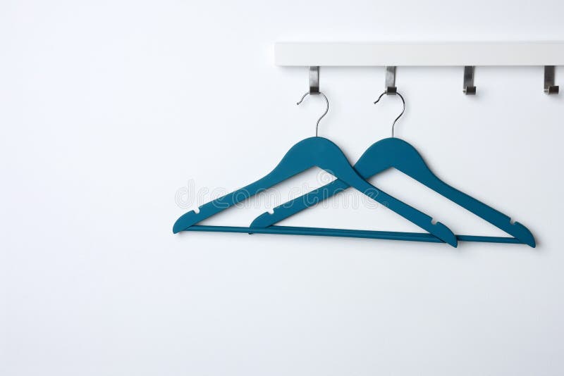 Rack with Empty Blue Clothes Hangers on White Wall Stock Image - Image ...