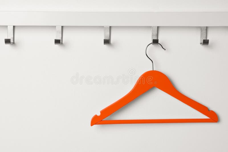 Rack with Empty Orange Clothes Hanger on White Wall Stock Photo - Image ...
