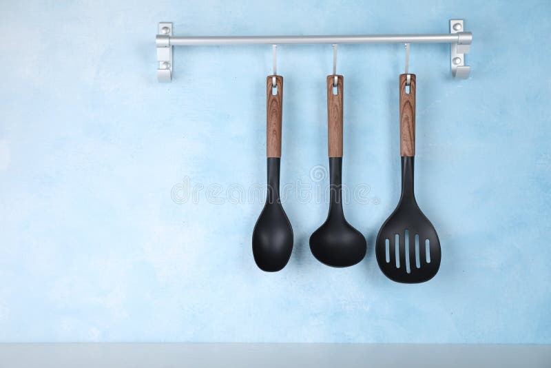 Rack with Kitchen Utensils Hanging on Light Blue Wall Stock Photo ...