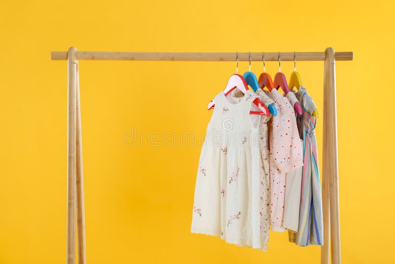 Rack with Stylish Children Clothes on Yellow Background Stock Image ...