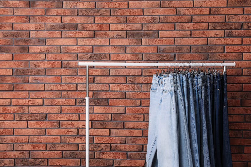 Rack with Stylish Jeans Near Wall Stock Photo - Image of canvas, cotton ...