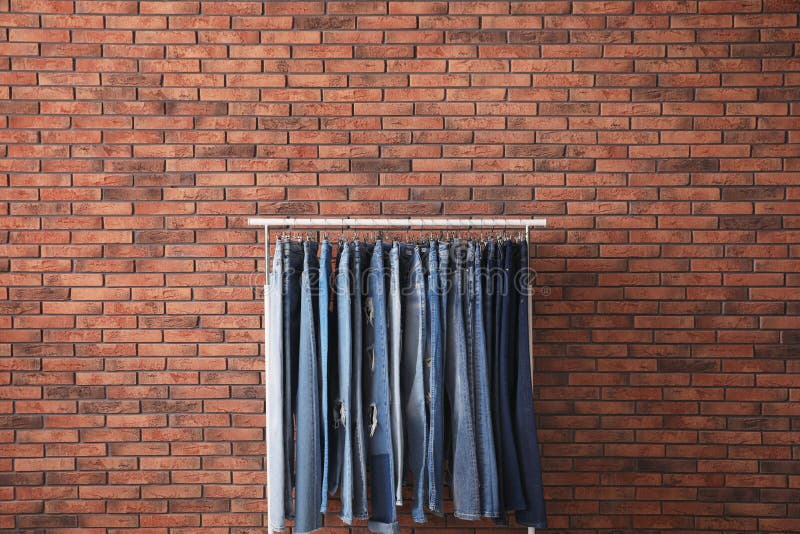 Rack with Stylish Jeans Near Brick Wall Stock Photo - Image of apparel ...