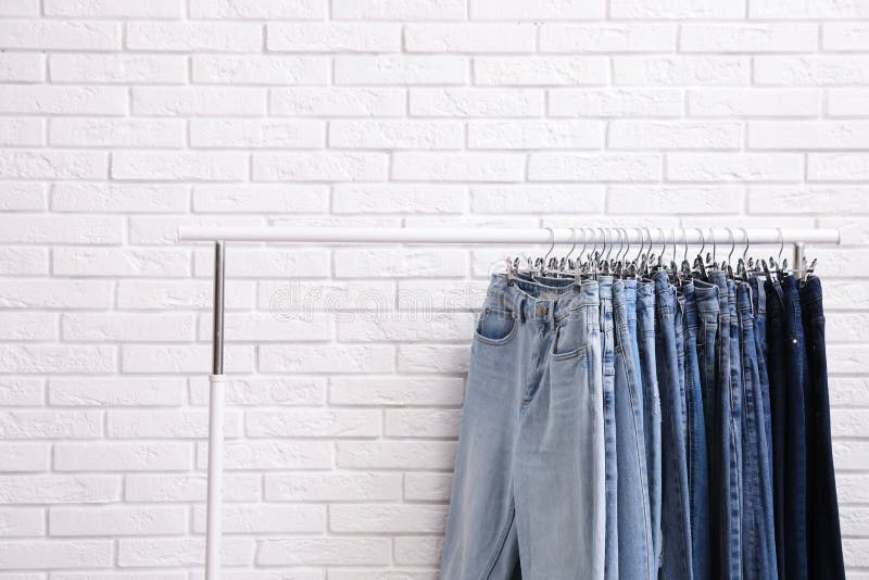 Rack with Stylish Jeans Near Wall Stock Image - Image of pants, luxury ...