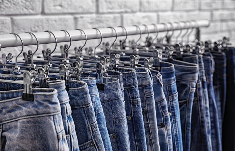 Rack with Stylish Jeans Near Brick Wall, Closeup Stock Photo - Image of ...
