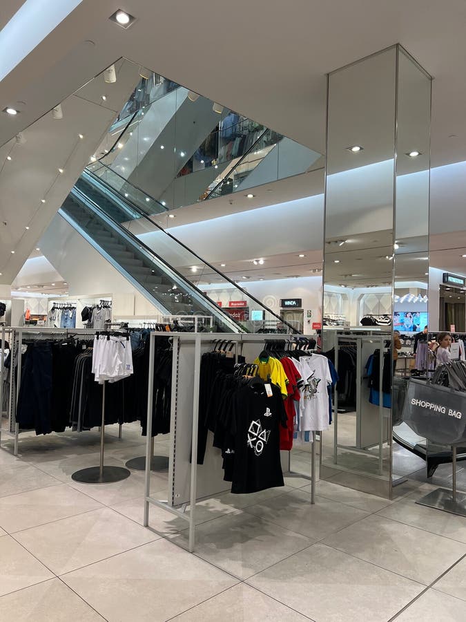 Racks with Stylish Clothes and Escalator in Shopping Mall Editorial ...