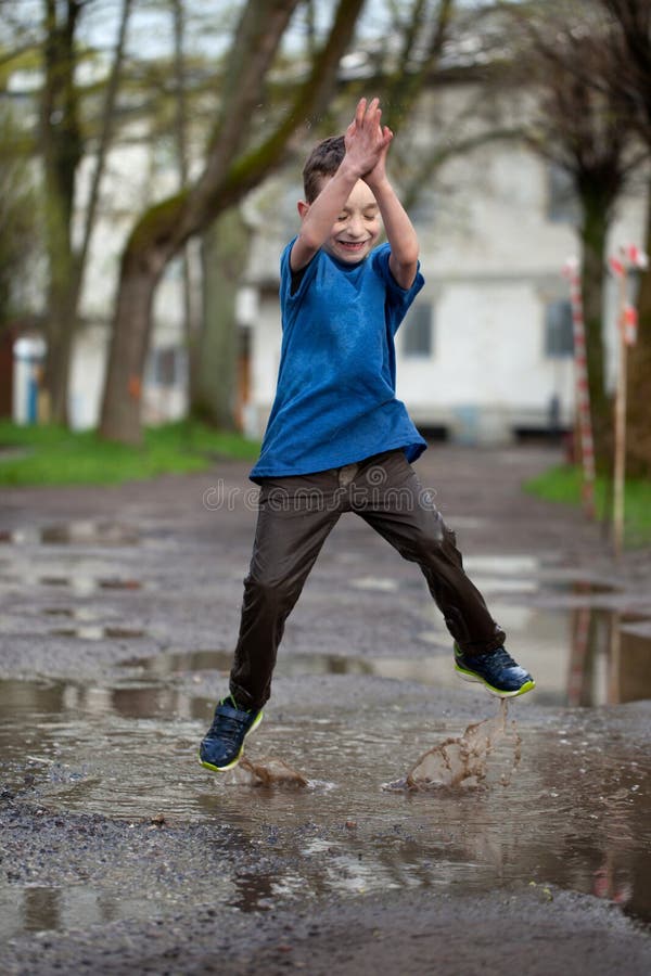 Ragazzino Che Spruzza in Una Pozza Di Fango, Fotografia Stock ...